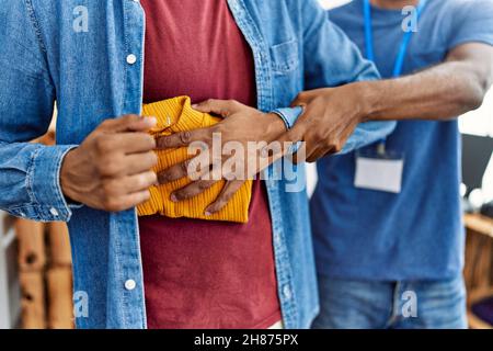 Two men shopkeeper and customer thief stealing clothes at clothing ...