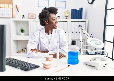 African dentist woman working at medical clinic looking away to side ...