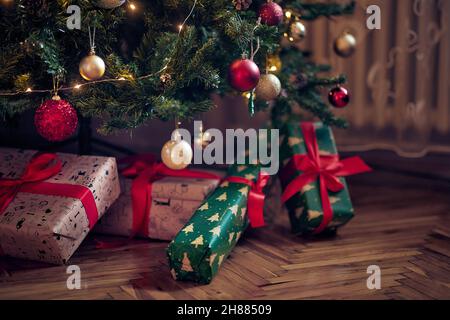 Beautiful Christmas gift boxes on floor near fir tree in room Stock ...