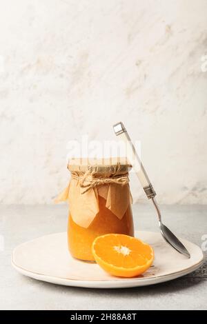 Plate with jar of tasty tangerine jam on light background Stock Photo ...