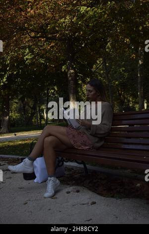 Pretty young woman reading interesting book in autumn park Stock Photo ...