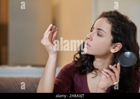 Young beautiful woman holding amethyst gemstone over isolated pink ...