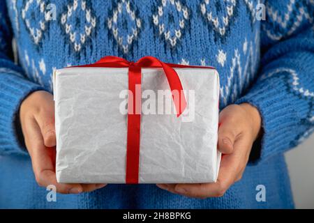 Woman in blue sweater with gift box for Valentine's Day on grey ...