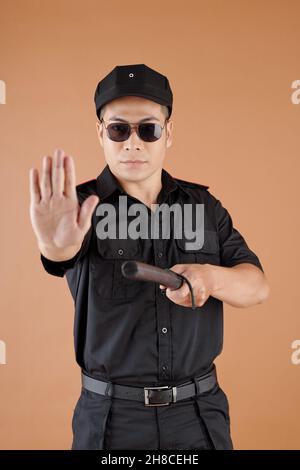 Serious armed police officer making stop gesture with hand. Side view ...