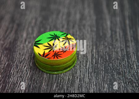 Close-up of grinder with symbols of marijuana and green yellow red ...