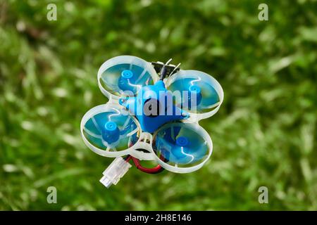 Small drone also race quad in blue, fly on brown wooden background ...
