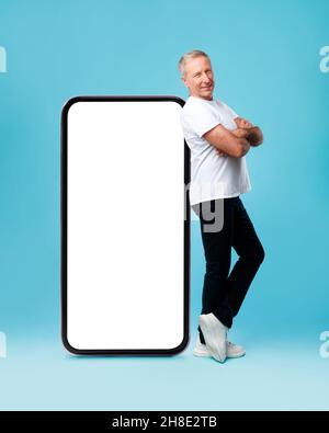 Elderly man leaning on a big weight scale and smiling isolated on white ...