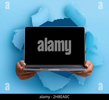 Person showing black empty laptop screen breaking through paper Stock ...