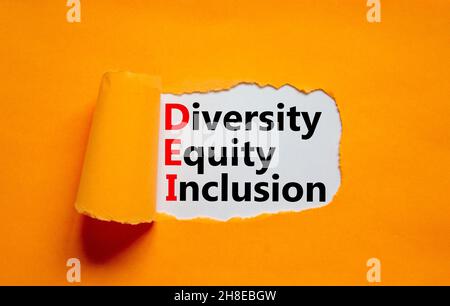 Diversity, equity, inclusion appearing behind torn paper background ...