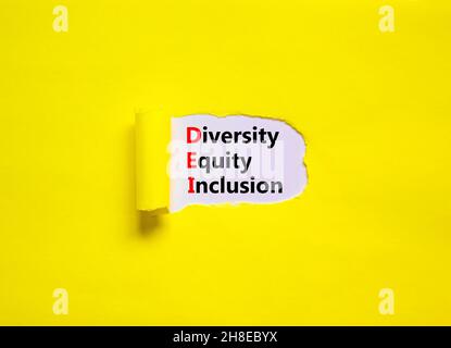 Diversity, equity, inclusion appearing behind torn paper background ...