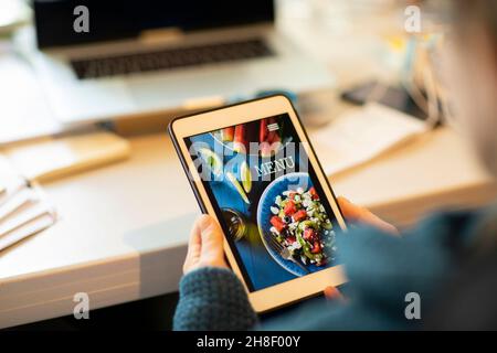 Woman looking at takeout menu on digital tablet Stock Photo - Alamy