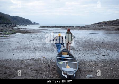 Young couple pulling canoe on beach, Kent, UK Stock Photo - Alamy