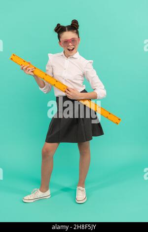 Back to school. School girl hold ruler measuring isolated on yellow ...