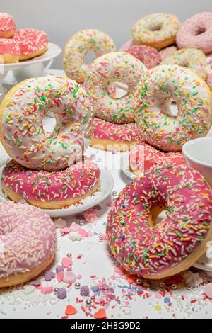 Table full of colorful donuts with sprinkles. White and pink donuts ...
