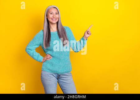 Photo of charming positive girl indicate thumb finger empty space ...