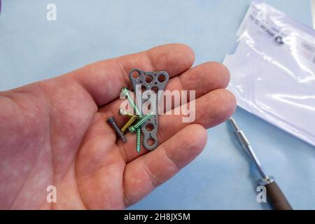 an explanted titanium plate and various titanium screws of a radius ...