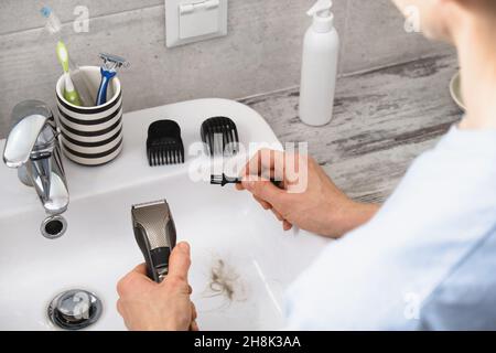 Man cleaning electronic shaving razor in sink, male self care and ...