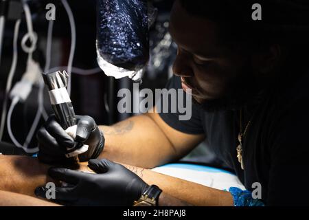 Tattoo master is busy with his work at tattoo studio. Close up Stock ...