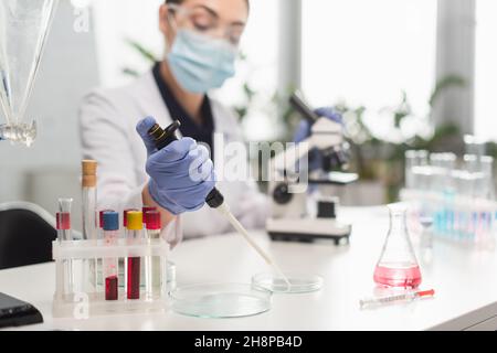 Blurred scientist in latex glove holding test tube with monkeypox ...