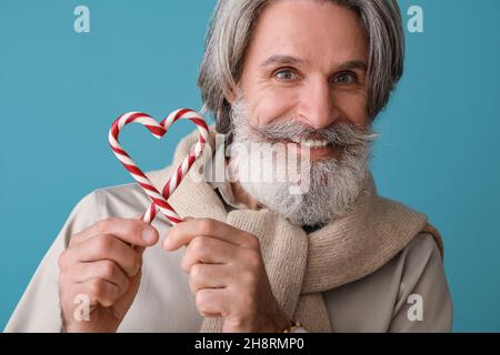 Senior man with sweet candy canes on color background Stock Photo - Alamy