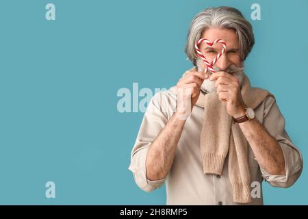 Senior man with sweet candy canes on color background Stock Photo - Alamy