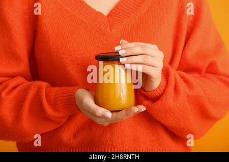 Woman holding jar of tasty tangerine jam on color background Stock ...