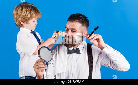 Son and father in barber shop. Shaving in barbershop. Assistant for dad ...