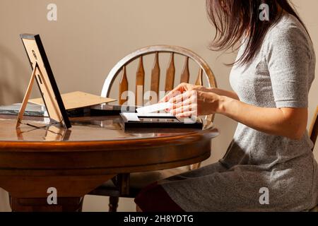 A young caucasian woman is placing a printed photograph into a picture ...