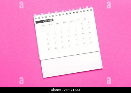 Flip paper calendar for April 2022, notebook, houseplant and calculator ...