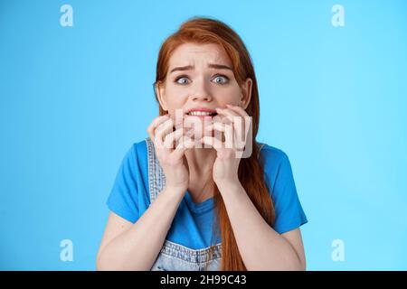 Anxious young woman trying to calm herself standing by window looking ...