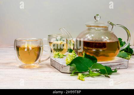 Teapot and two cups of tea with a linden tree on a wooden table ...