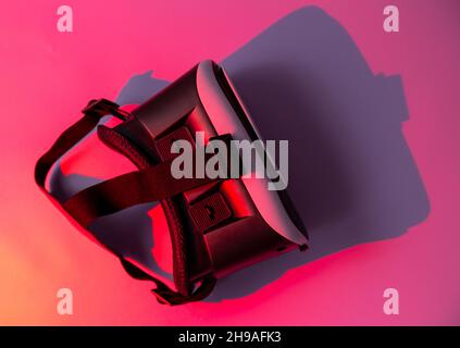 Virtual reality glasses, headphones on a pink background with orange ...