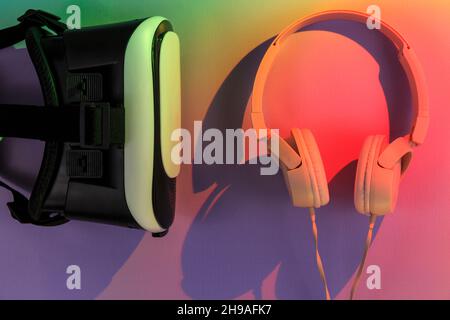 Virtual reality glasses, headphones on a pink background with orange ...