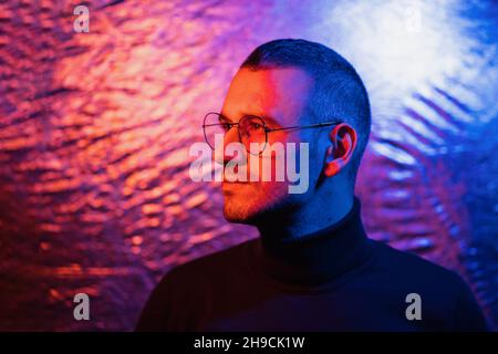 Neon portrait of serious man wearing glasses with black frame and dark ...