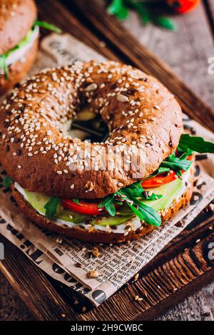 Bagels with cream, avocado, salmon, tomatos on table beige background ...
