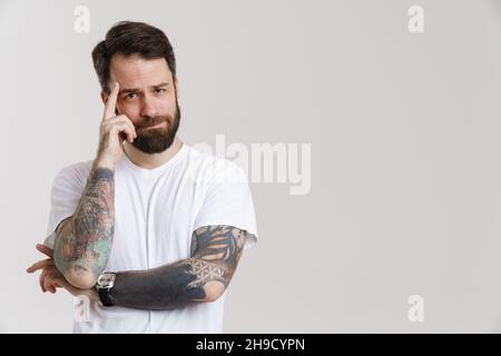 Bearded puzzled man touching his forehead and looking at camera ...