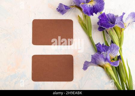 Brown business card with lilac iris flowers on white concrete ...