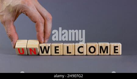 Welcome or unwelcome symbol. Businessman turns wooden cubes and changes ...