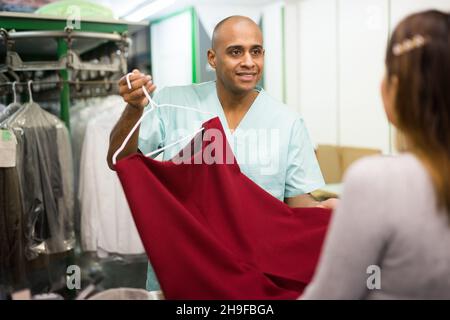 Laundry employee handing out clean clothes to client Stock Photo - Alamy