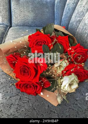 Red roses wrapped in brown kraft paper and tied with a red ribbon on a ...