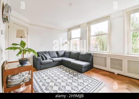 Comfortable couch located near carpet and table against window in ...