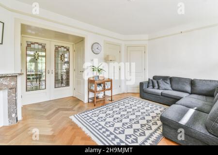 Comfortable couch located near carpet and table against window in ...