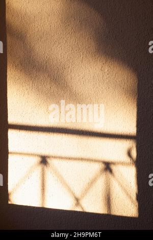 Abstract shadow silhouette of window frame from sunbeam on wall in room ...