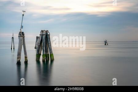 Wooden posts with lanterns at the entrance to a harbour, Venice, Italy ...