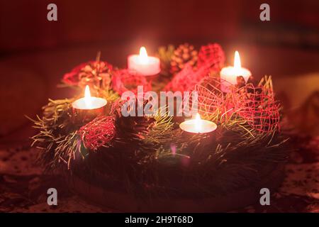 Christmas wreath with glowing lights and candles on mantelpiece near ...