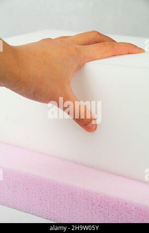 the hand presses on the surface of the rubber foam. Checking hardness ...