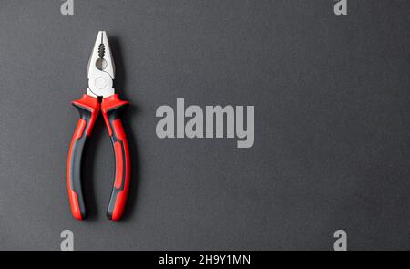 Pliers in red and black colored on a black background with blank text ...