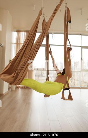 Rear view of a female gymnast doing splits with her hands behind her ...