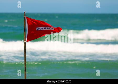 Red flag life guard danger warning sign on the beach. No swimming it's ...
