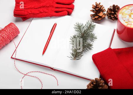 Beautiful winter composition with open notebook, gloves, hat and cup of ...